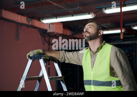 good looking hardworking technician standing next to step ladder and ...