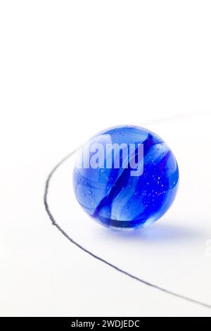 A blue glass marble inside a drawn circle Stock Photo - Alamy