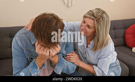 Mother and son share supportive hug, sitting on sofa at home, family tackles sadness and anxiety ...