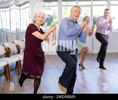 Mature positive people dancing twist together at dance studio Stock ...