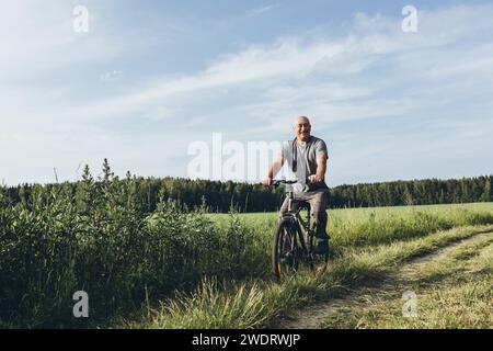 Joyful senior man riding a bike in a park on a beautiful sunny day ...