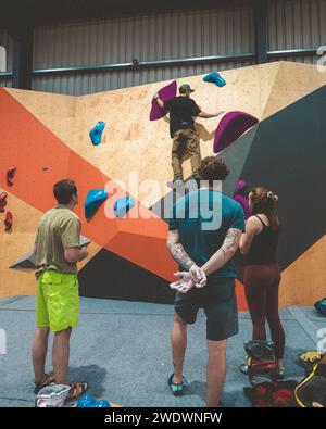 A group of people are gathered around a wall covered in colorful sticky ...