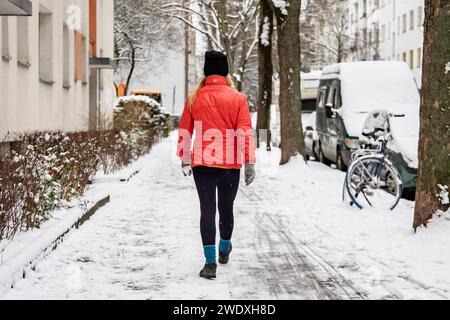 Menschen laufen auf dem Gehweg gedeckt mit Schnee und Eis in Berlin ...