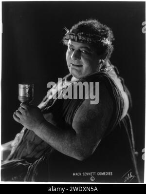 Actor from Mack Sennett comedy film in Roman toga seated holding wine ...