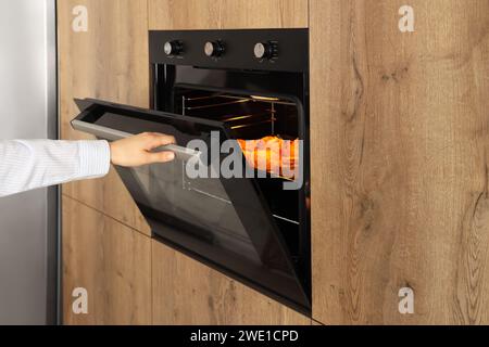 Woman opening oven with buns in kitchen Stock Photo - Alamy