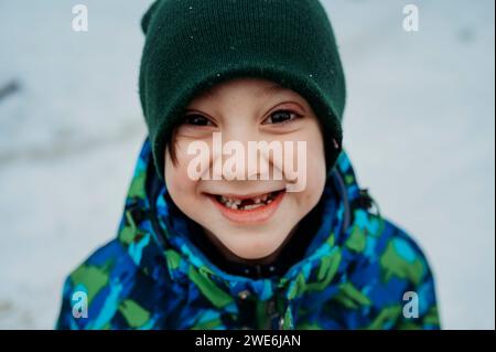 A happy boy in a winter hat and snow-covered mittens. A child in winter with ice sleds Stock ...