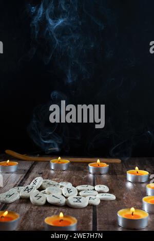 Circle of lighted candles with stone runes in the center, on the black ...