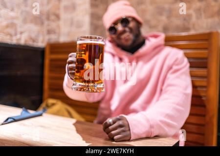 Cool african man toasting with a glass of beer sitting in a bar Stock ...