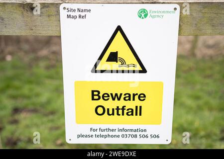 Yellow, black and white beware outfall sign Stock Photo - Alamy