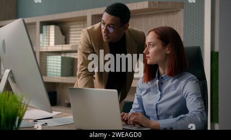 Mentor training intern, explaining data on laptop Stock Photo - Alamy