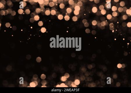Peach fuzz blurred abstract bokeh lights on black background. Snowy shiny glitter sparkle stars ...