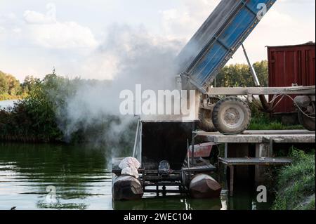 Feeding fish in a fish farm. Loading fish feed into the boat from the ...