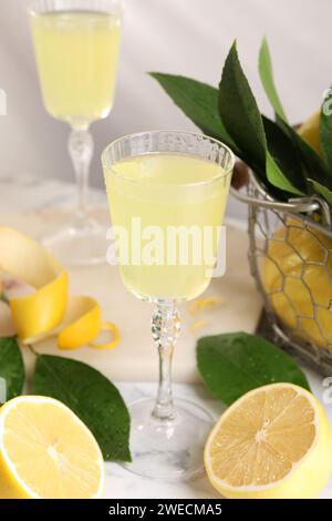 Tasty limoncello liqueur, lemons and green leaves isolated on white ...