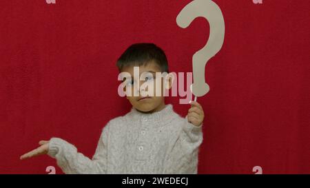 Cute child questioning something. Holding question mark , isolated on ...