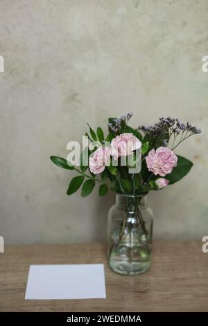 Vase with beautiful rose flowers, blank card and gift box on table near ...