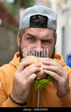 Hunger Man eat burger outdoor. Man eat tasty Hamburger on street ...