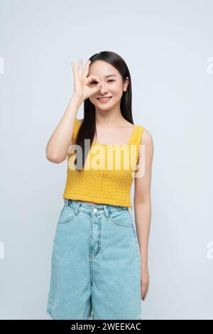 Young beautiful woman doing ok gesture with hand smiling, eye looking ...