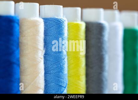 Multi-colored threads on spools and a steel needle. Macro photography ...