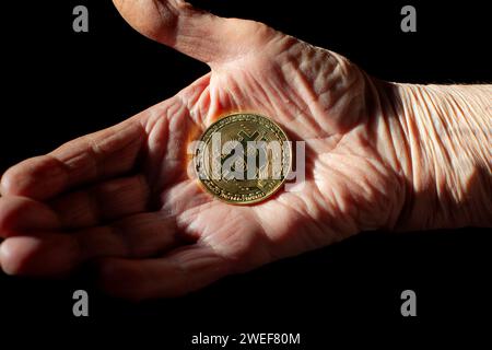 Golden Bitcoin token coin palm of a male hand with green nature ...