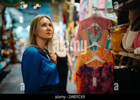 Woman choosing a clothes at the evening bazaar Stock Photo - Alamy