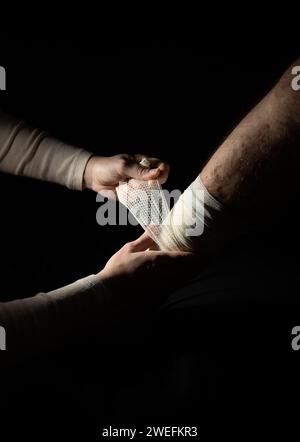 Nurse removing a bandage from a male patient with a black background ...