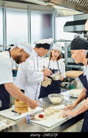 good looking mature chief cook working with his multicultural chefs on ...