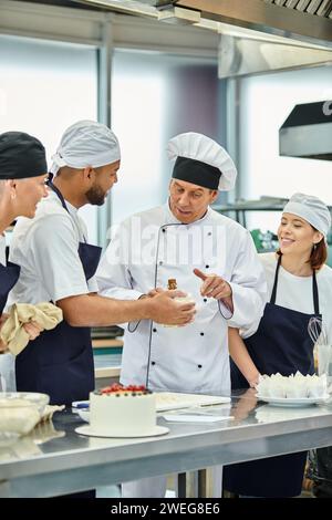 good looking mature chief cook working with his multicultural chefs on ...