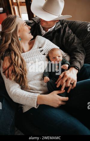 Newborn baby boy cuddled by mom and dad on the couch Stock Photo - Alamy