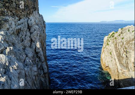A natural limestone cliff majestically towers over the serene blue sea ...