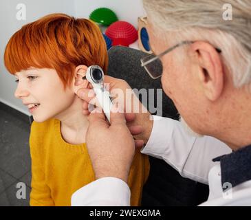 Audiologist examining child's ear with otoscope. Otoscopy and hearing ...