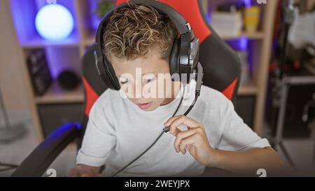 Blond boy streamer playing video game using computer at gaming room ...