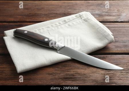 One sharp knife and napkin on wooden table, top view. Space for text ...