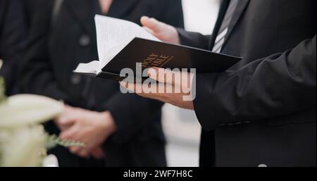 Bible, hands and family at funeral, cemetery or burial ceremony ...