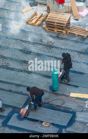 Construction workers doing waterproofing work on a building ceiling ...