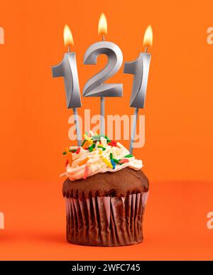 Birthday cupcake with number 121 candle - Sparkling orange background ...