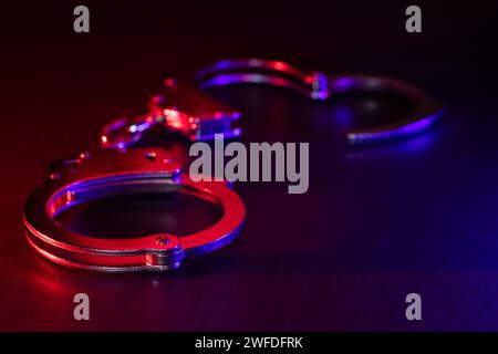 Closed handcuffs on the street pavement at night with police car lights ...