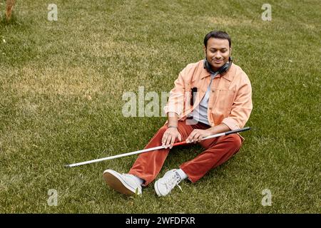 cheerful indian blind man in orange jacket with helping stick walking ...