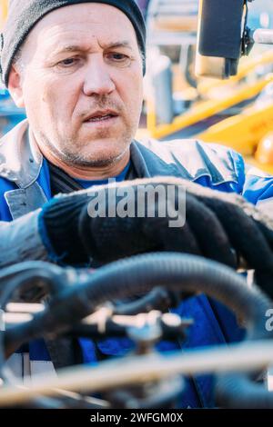 Mechanic repairs engine of tractor or heavy equipment. Farmer inspects ...