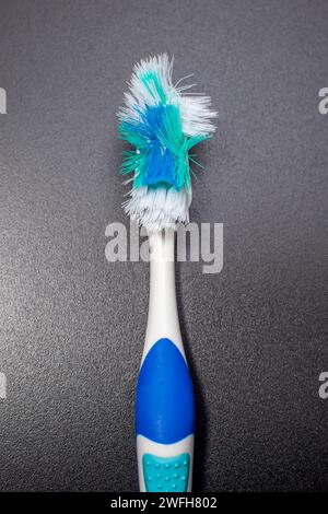 Top view of an old worn toothbrush with bent bristles on a wood counter ...
