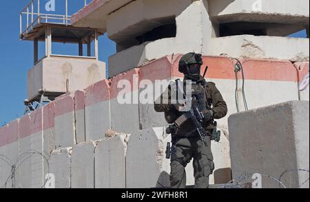 An Israeli soldier stands guard at the Nitzana crossing where trucks ...