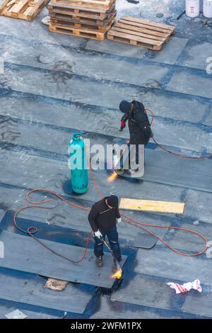 Construction workers doing waterproofing work on a building ceiling ...
