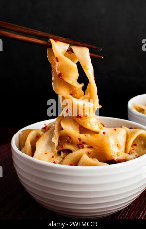 Close-up of chopsticks holding a spicy kimchi pork dumpling Mandu ...