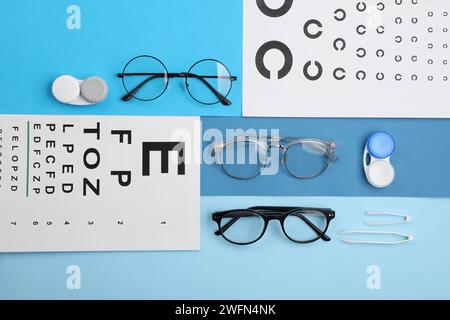 Vision test charts, glasses and lenses on light blue background, flat ...