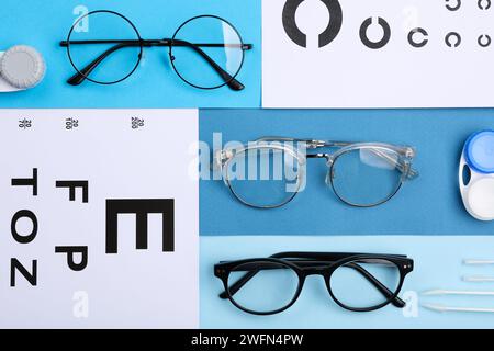 Vision test charts, glasses, lenses and tweezers on light blue ...