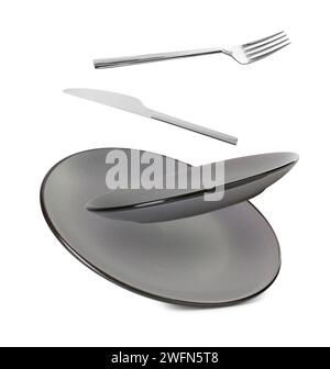 Clean plates, fork and knife falling on white background Stock Photo ...