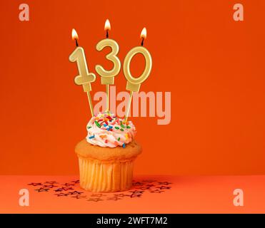 Candle number 130 - Birthday in orange background Stock Photo - Alamy