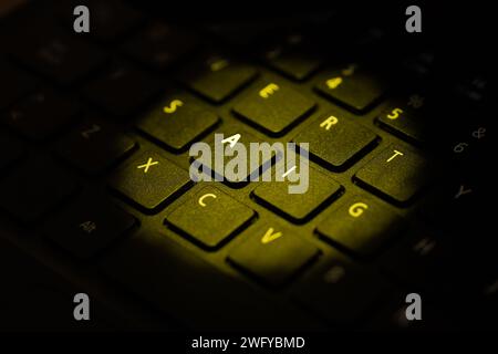 keyboard being illuminated with yellow light highlighting letters a i ...
