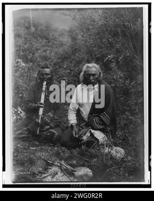 A smoke, c1905. Two Crow Indians in Montana, sitting on the ground, one ...