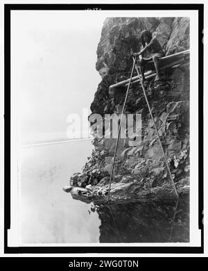 This photograph shows a Native American fisherman using a dip net ...
