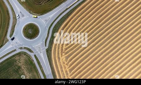 Roundabout between fields and meadows, rows of straw on a harvested ...